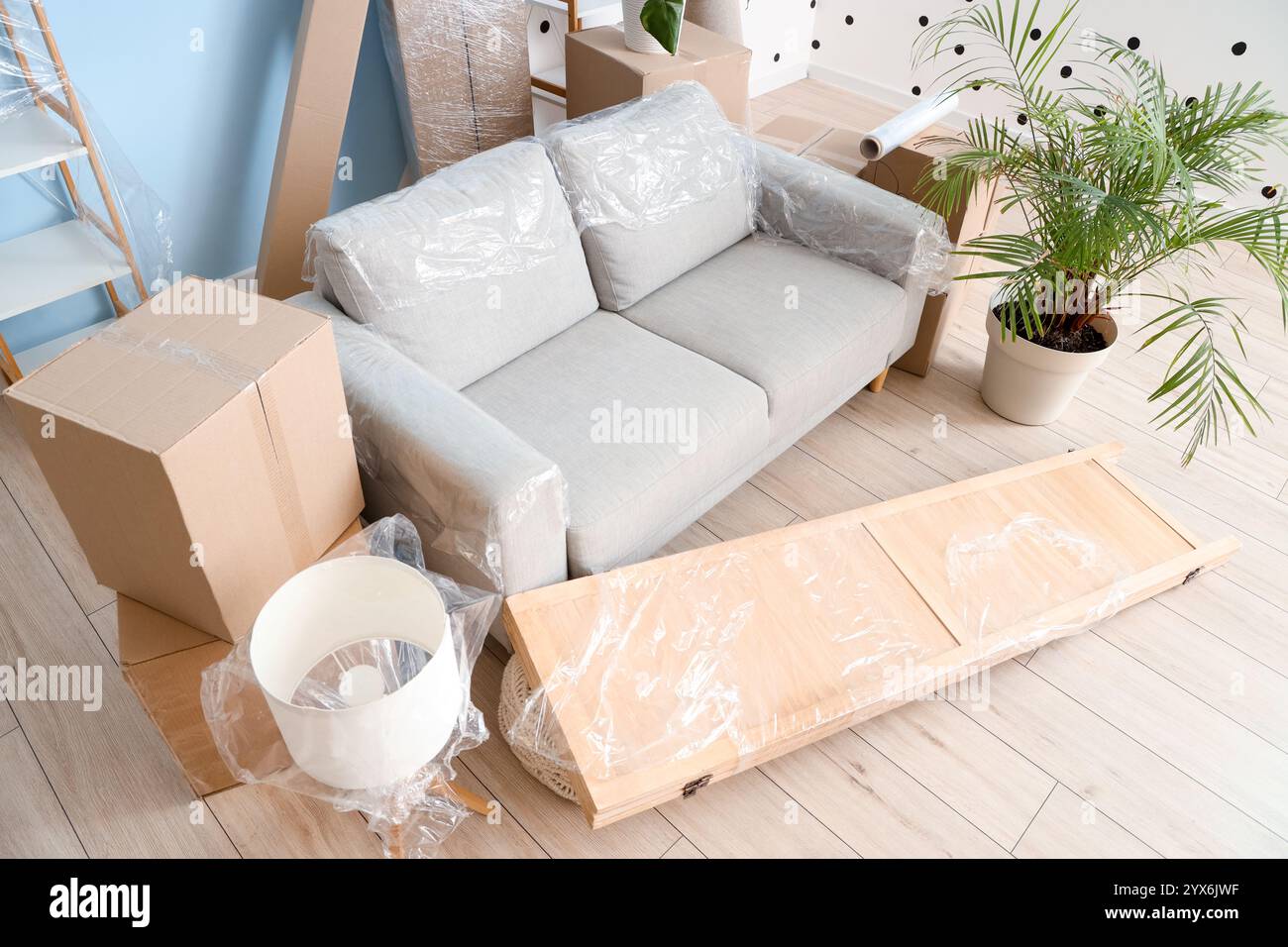 Moving boxes with stretch wrap and furniture in living room Stock Photo ...
