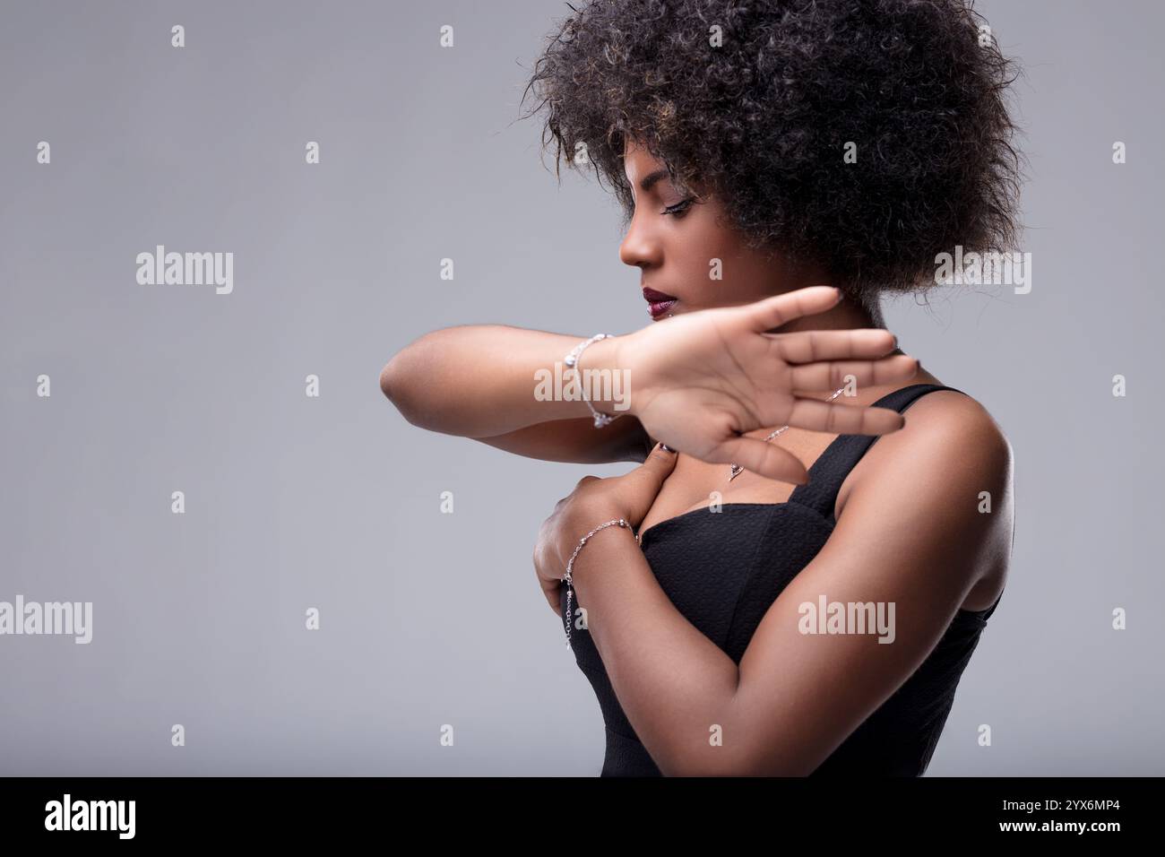Studio portrait of a young woman with curly hair, making a defensive ...