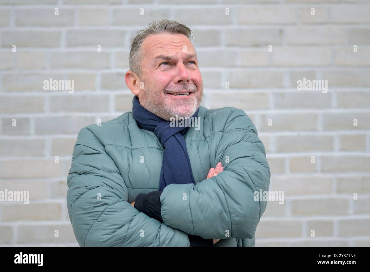 A middle-aged man dressed in a green quilted jacket and dark scarf ...