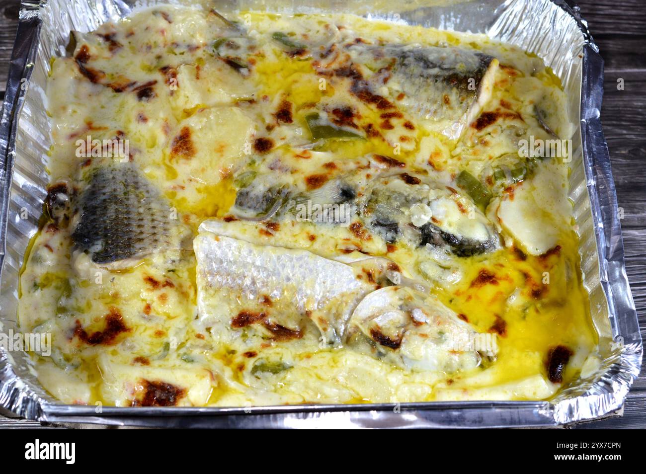 Baked mullet fishes with creamy white sauce, pieces and slices of ...