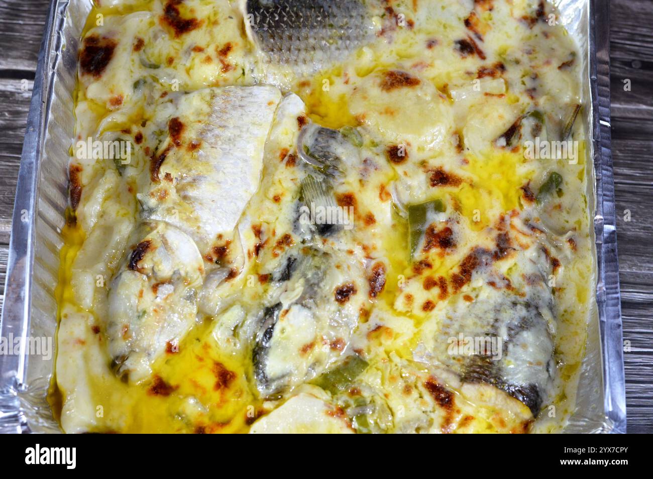 Baked mullet fishes with creamy white sauce, pieces and slices of ...
