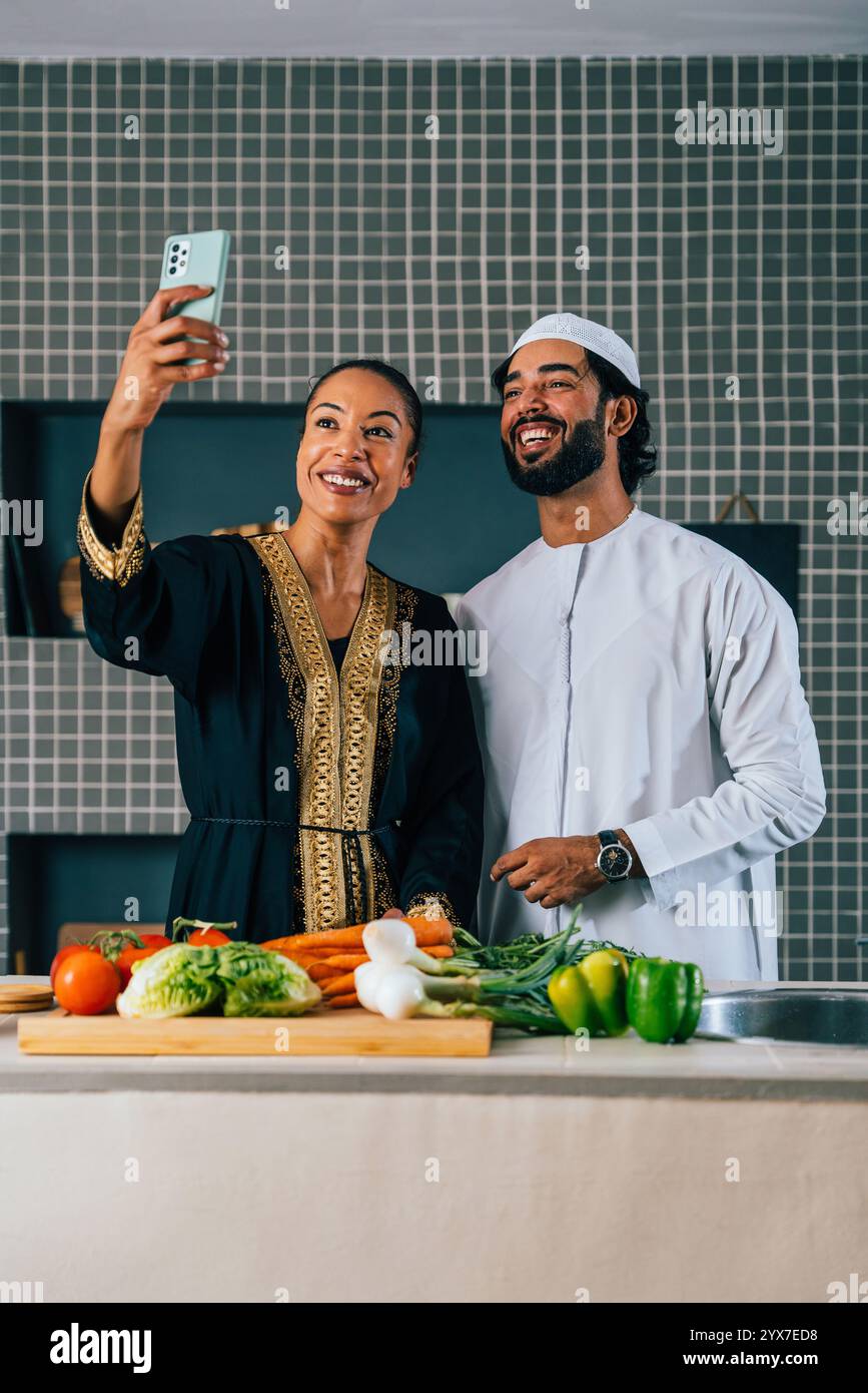 Happy beautiful young arab couple with emirati clothing together at home - Middle-eastern man ...
