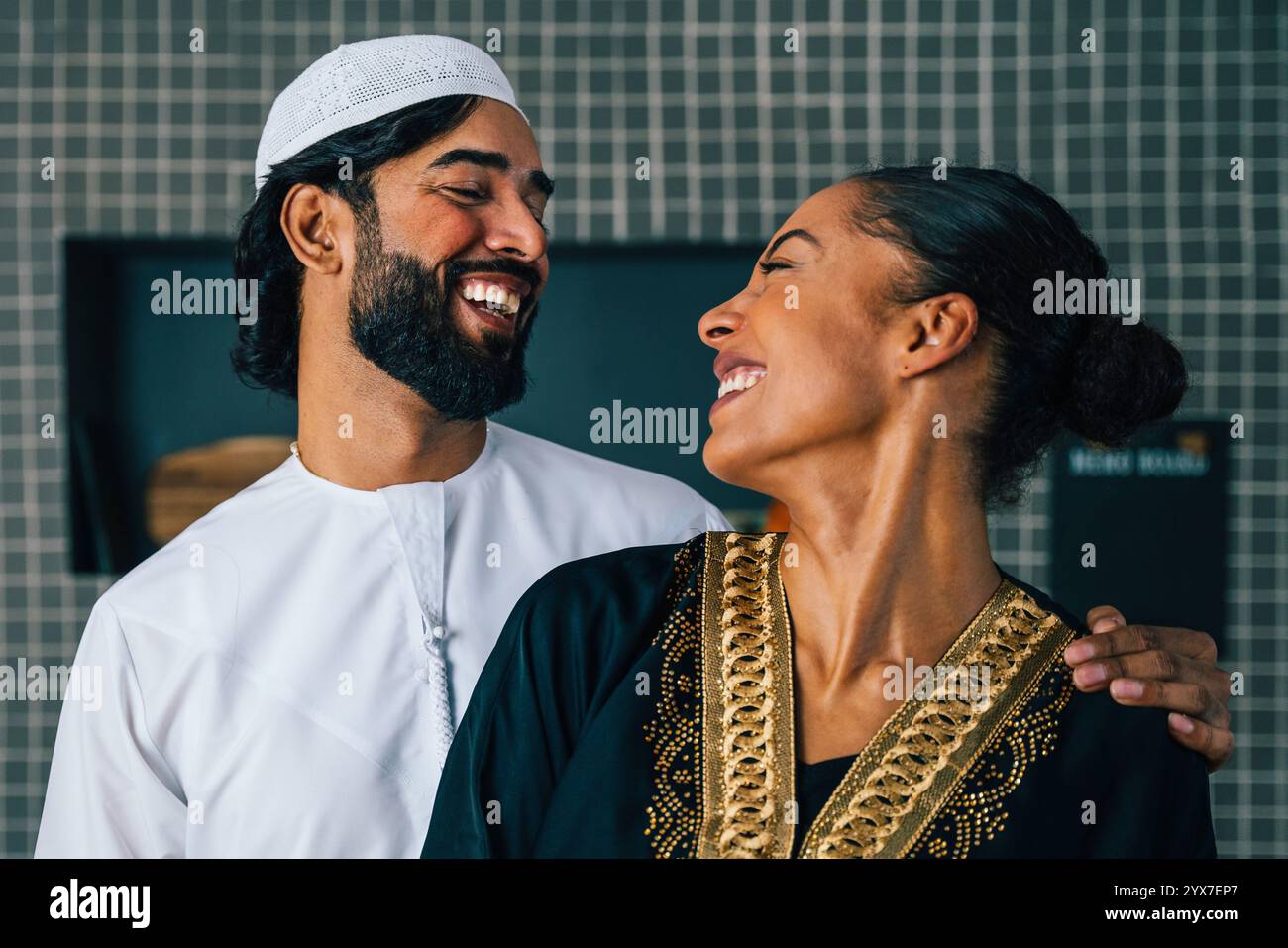Happy beautiful young arab couple with emirati clothing together at home - Middle-eastern man ...