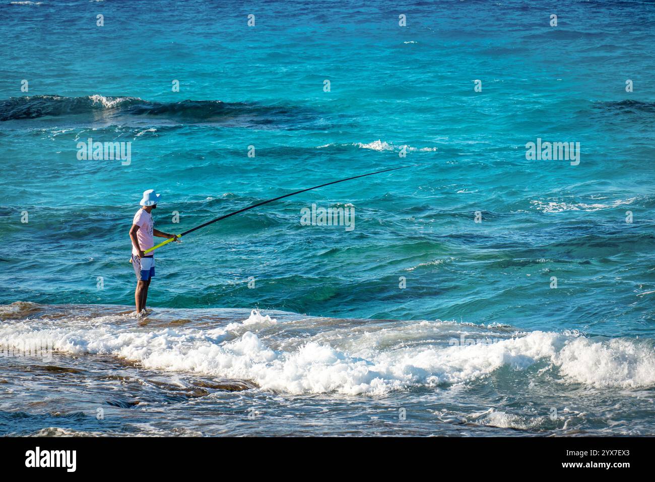 A man fishing by the pristine turquoise waters of Mersa Matruh, Egypt ...