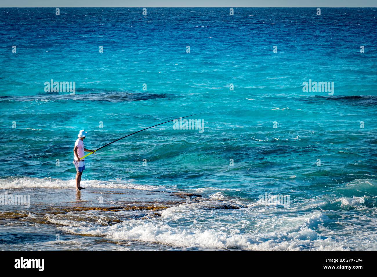 A man fishing by the pristine turquoise waters of Mersa Matruh, Egypt ...