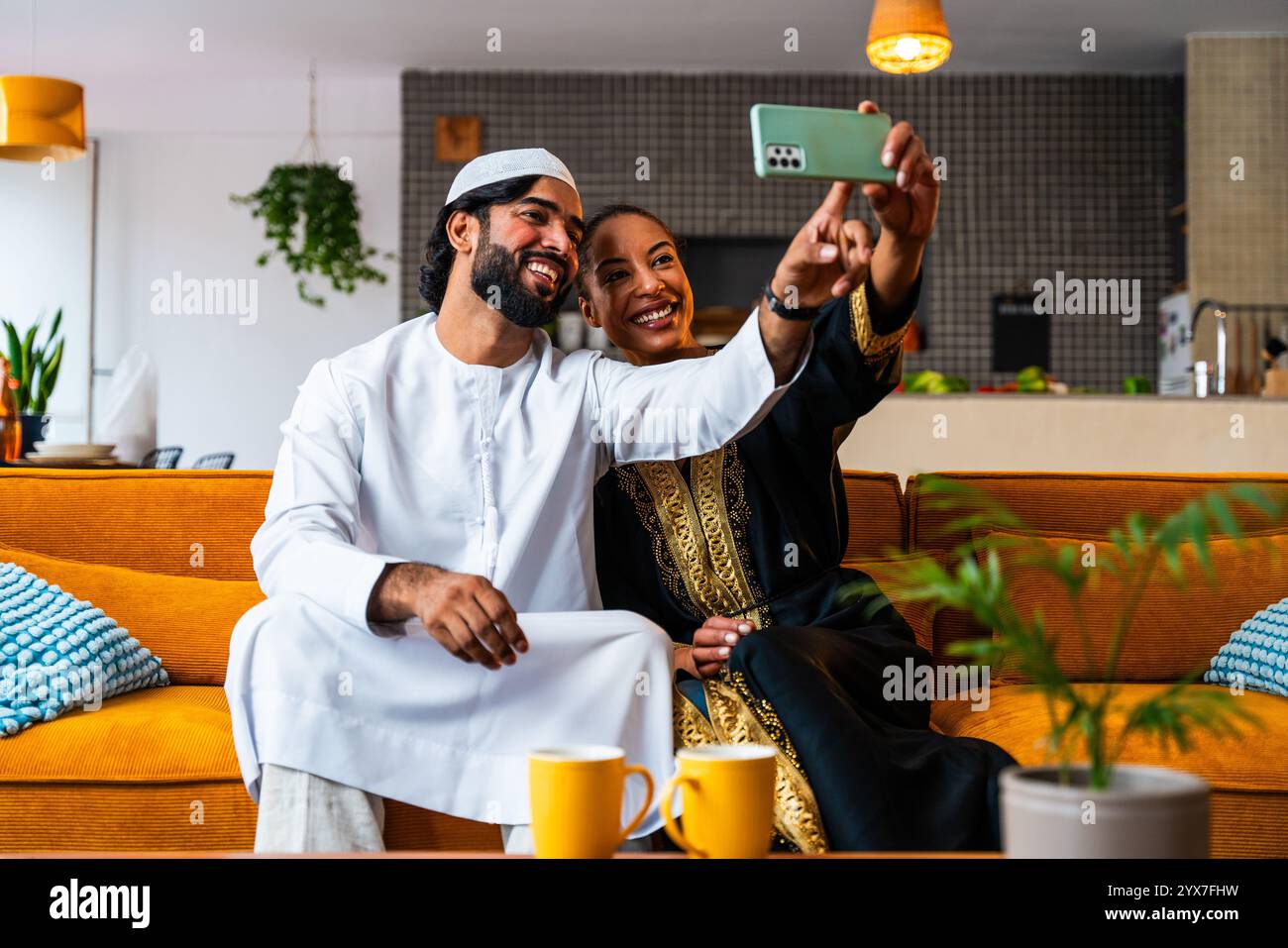 Happy beautiful young arab couple with emirati clothing together at home - Middle-eastern man ...