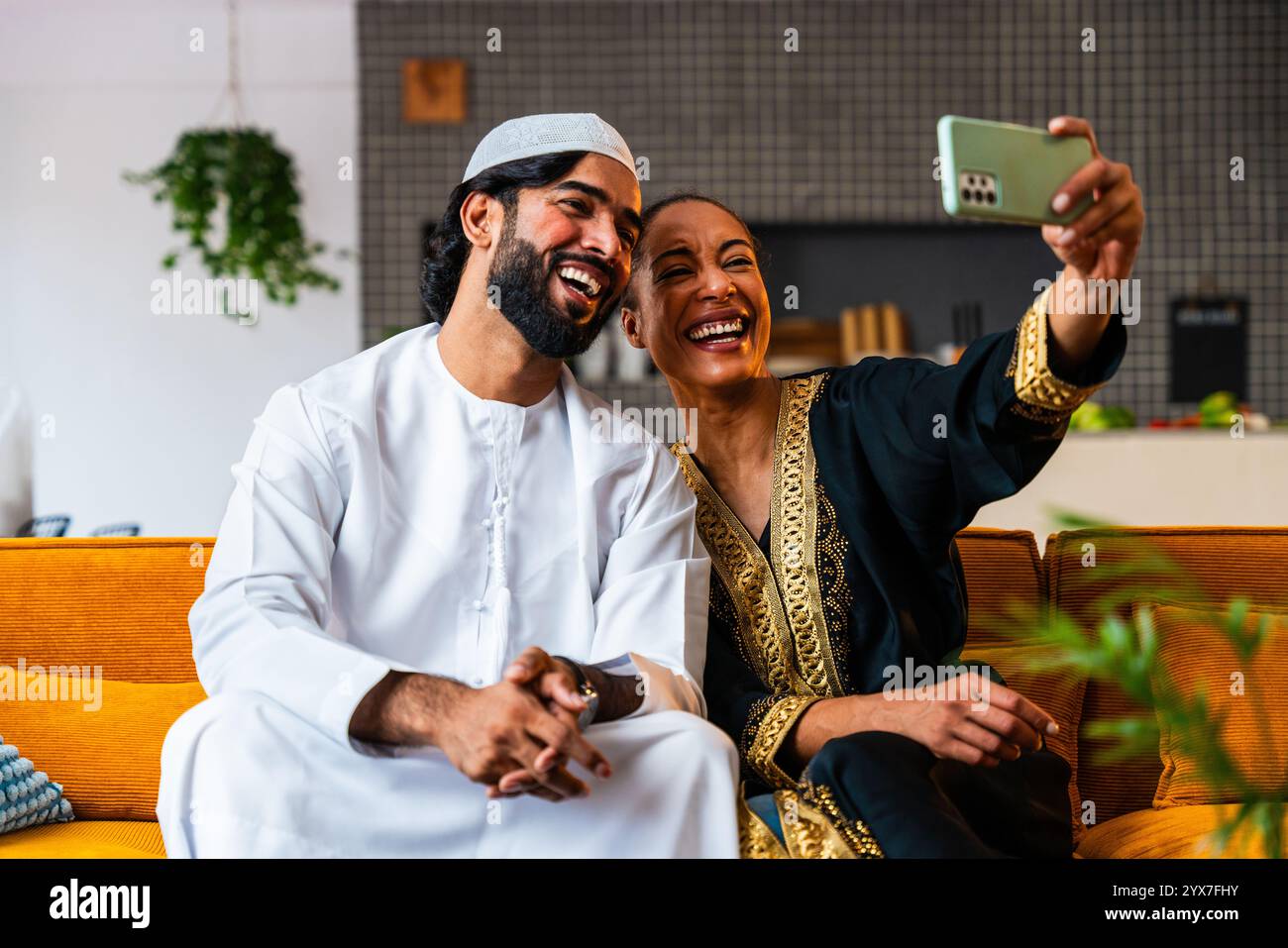 Happy beautiful young arab couple with emirati clothing together at home - Middle-eastern man ...