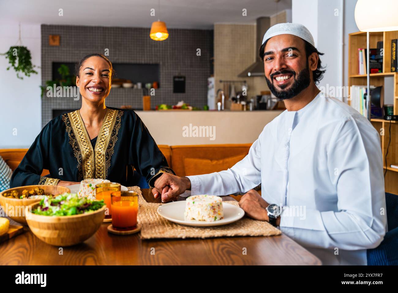 Happy beautiful young arab couple with emirati clothing having lunch together at home - Middle ...