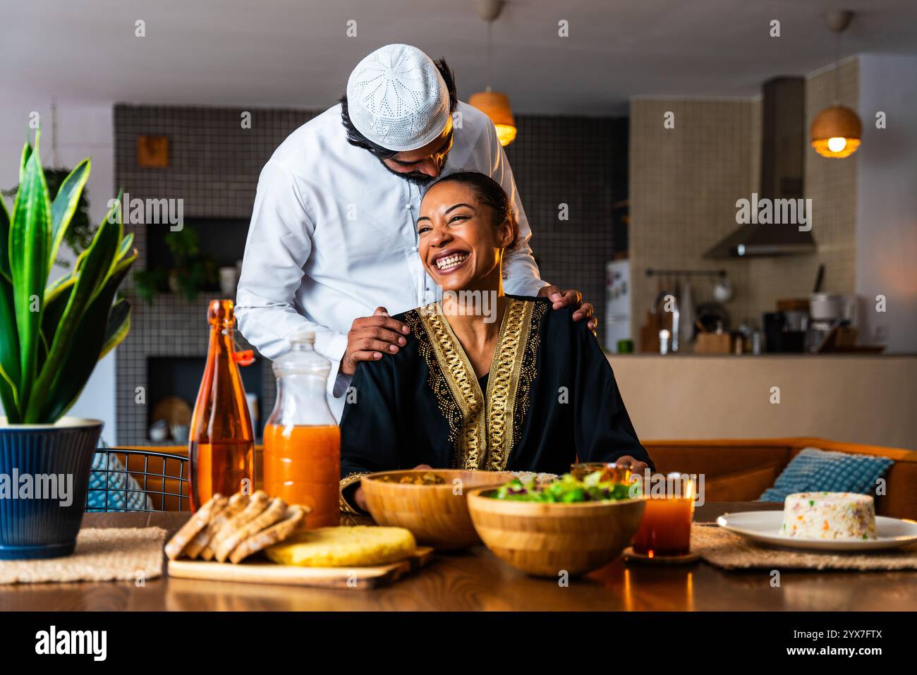 Happy beautiful young arab couple with emirati clothing having lunch together at home - Middle ...