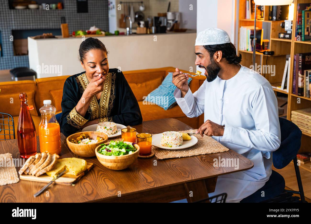 Happy beautiful young arab couple with emirati clothing having lunch ...