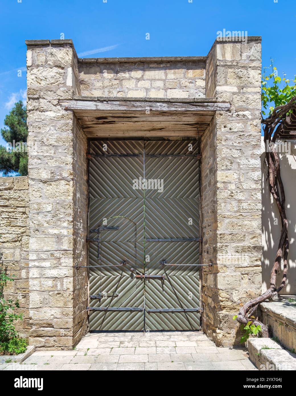 A striking stone gate with a zigzag wooden design stands tall in a well ...