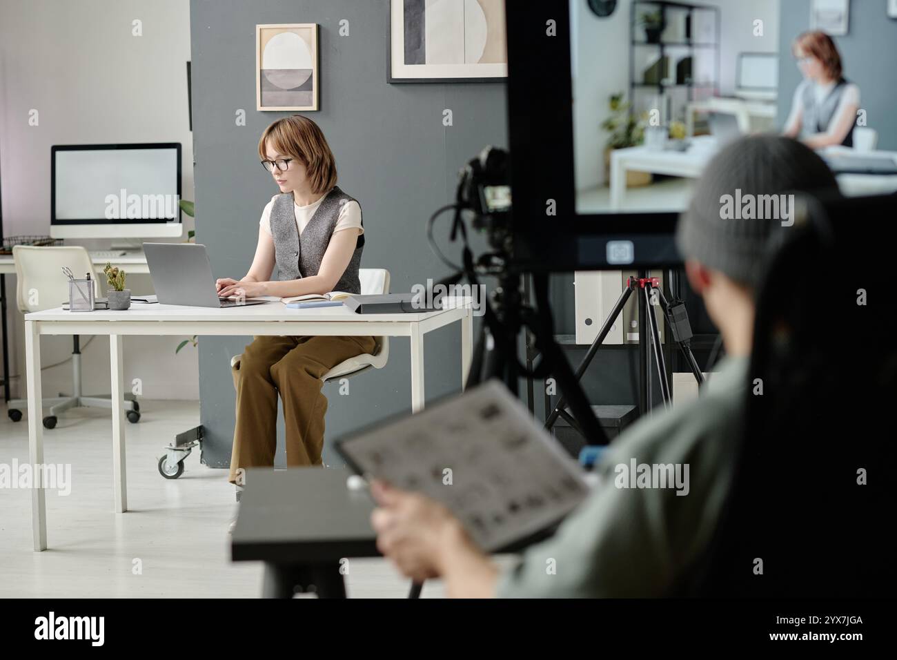 Elegant actress sitting at work desk and typing on keyboard while ...