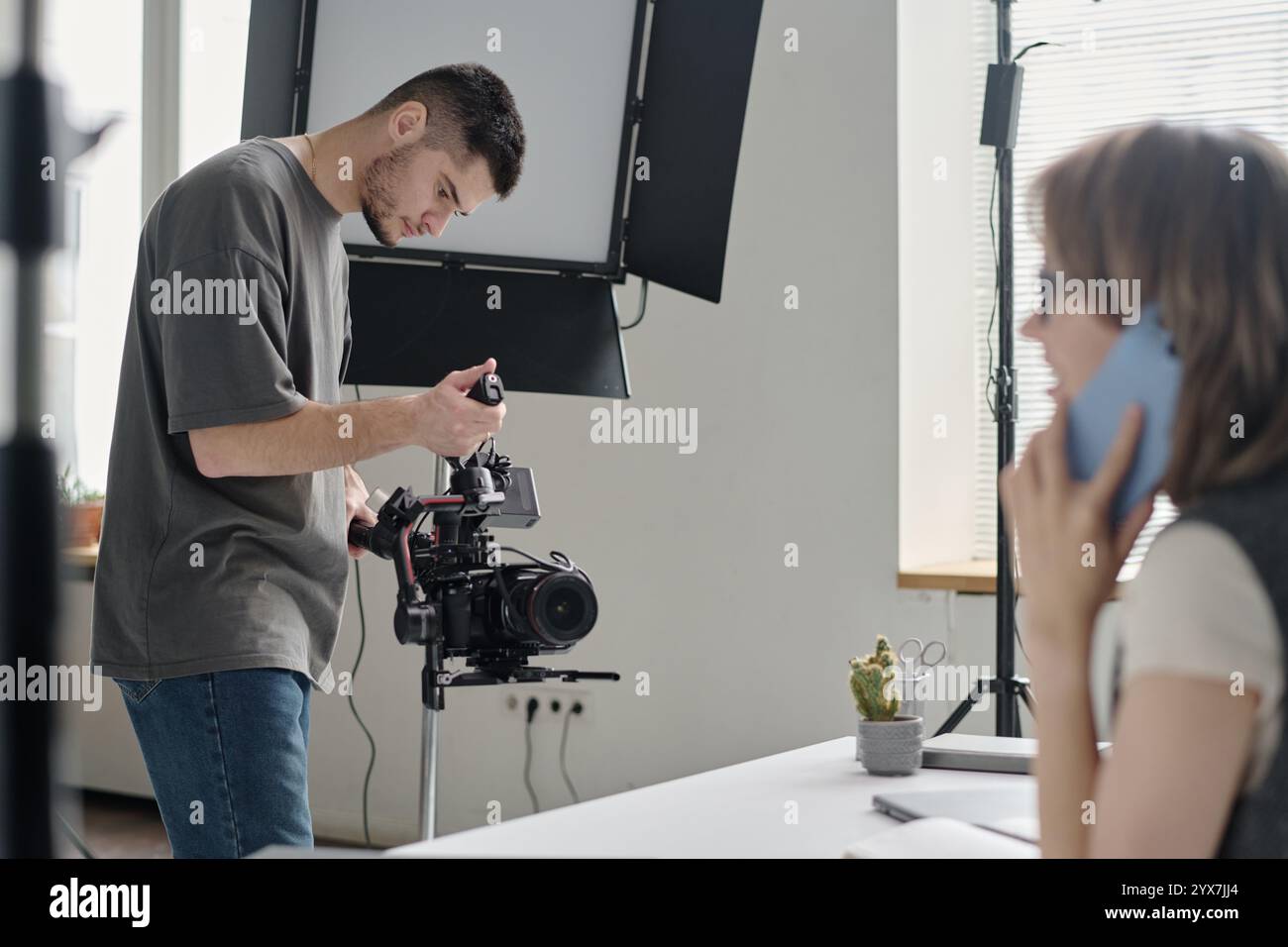 Young adult Caucasian cameraman using professional huge camera to shoot ...