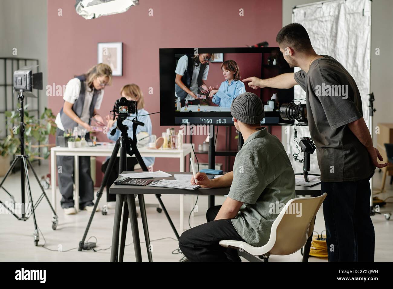 Back view of director and operator looking at huge monitor with actress ...