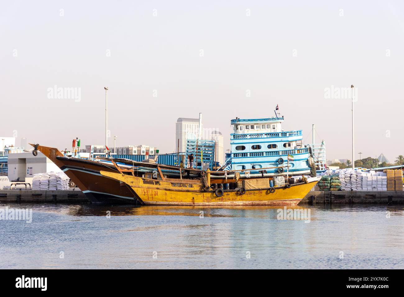 A traditional wooden cargo ship docked at a port in Riggat Al Buteen in ...
