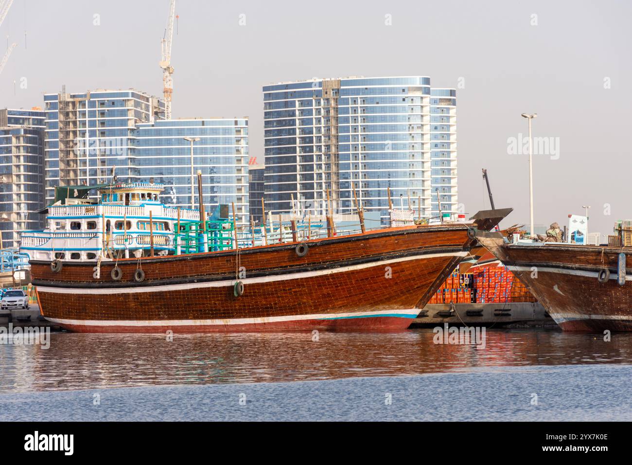 A traditional wooden cargo ship docked at a port in Riggat Al Buteen in ...