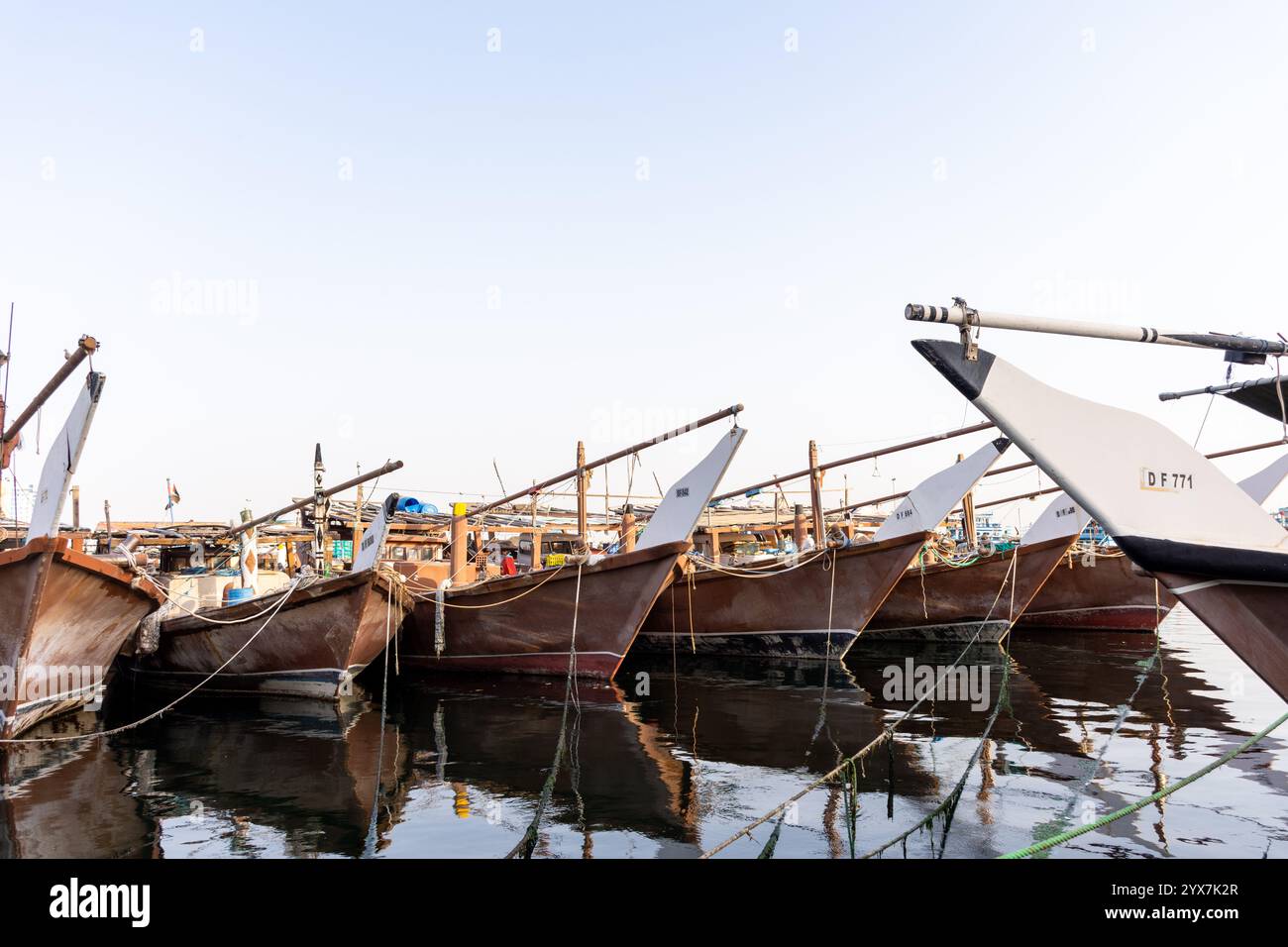A row of traditional wooden boats docked at a port in Riggat Al Buteen ...