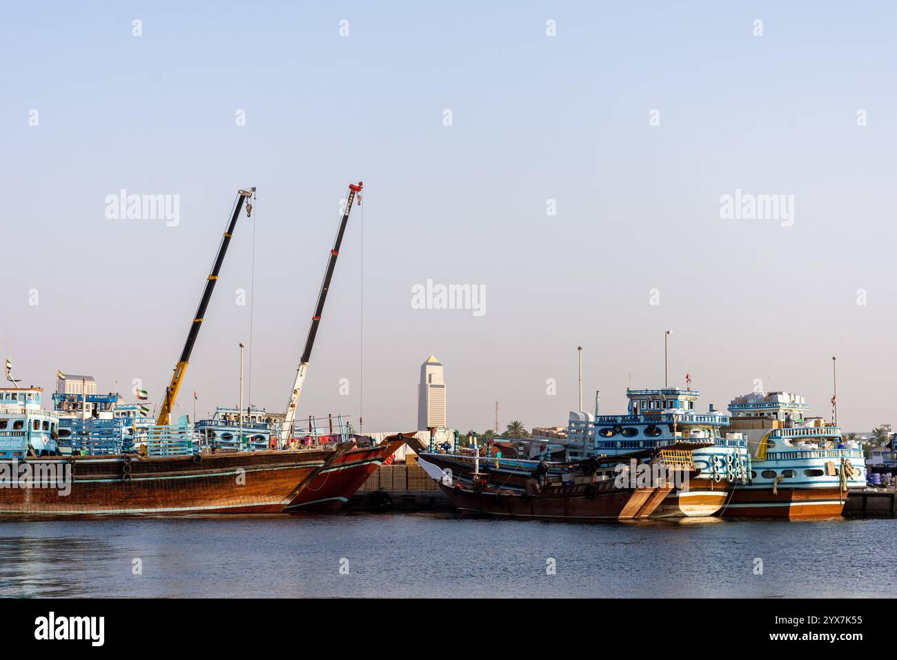 A row of traditional wooden boats docked at a port in Riggat Al Buteen ...