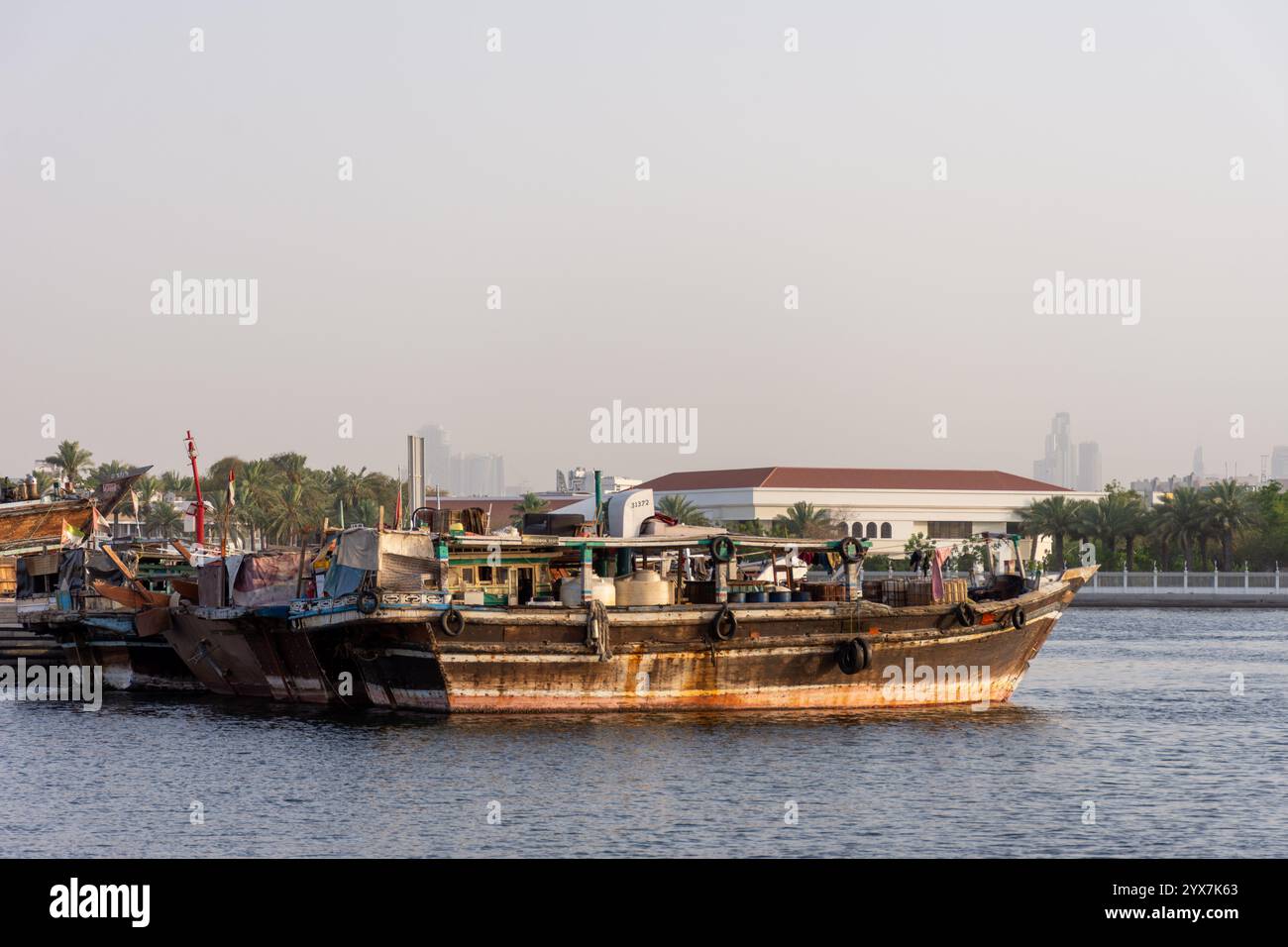 A traditional wooden cargo ship docked at a port in Riggat Al Buteen in ...