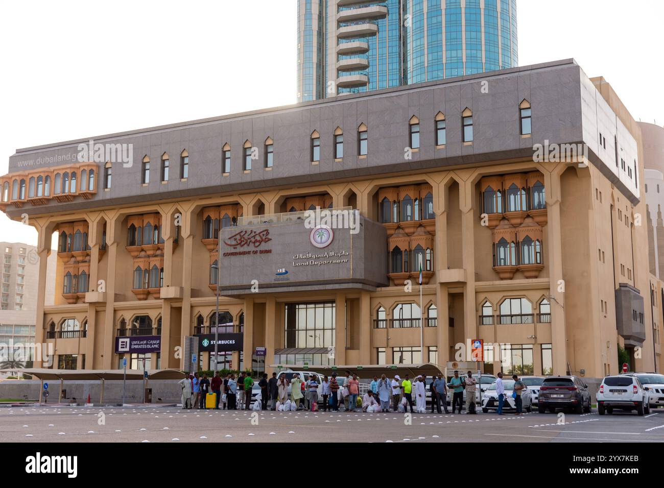 A crowd of people standing in front of the Dubai Land Department ...