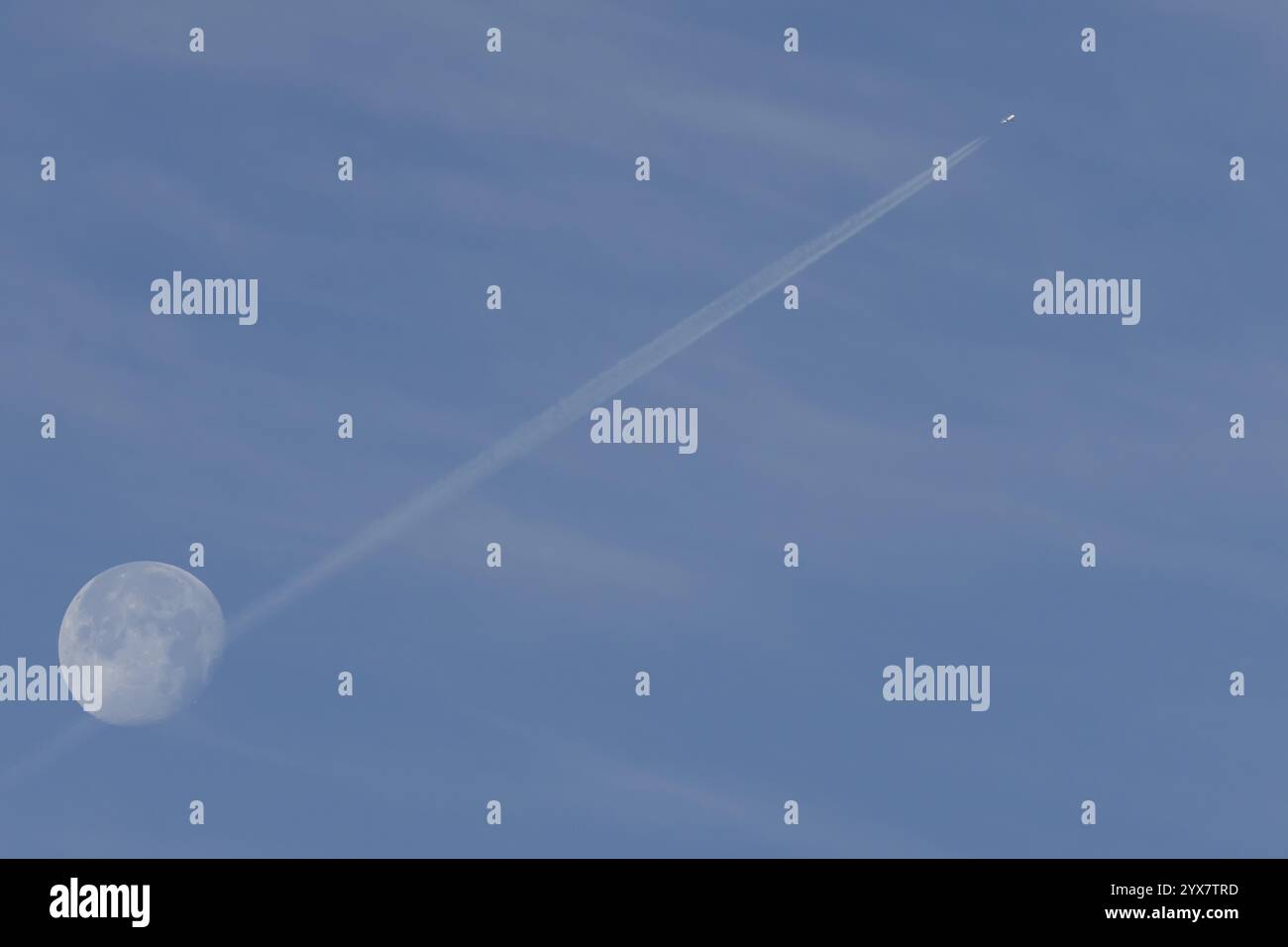 Jet passenger aircraft flying in a blue sky passing by the moon ...