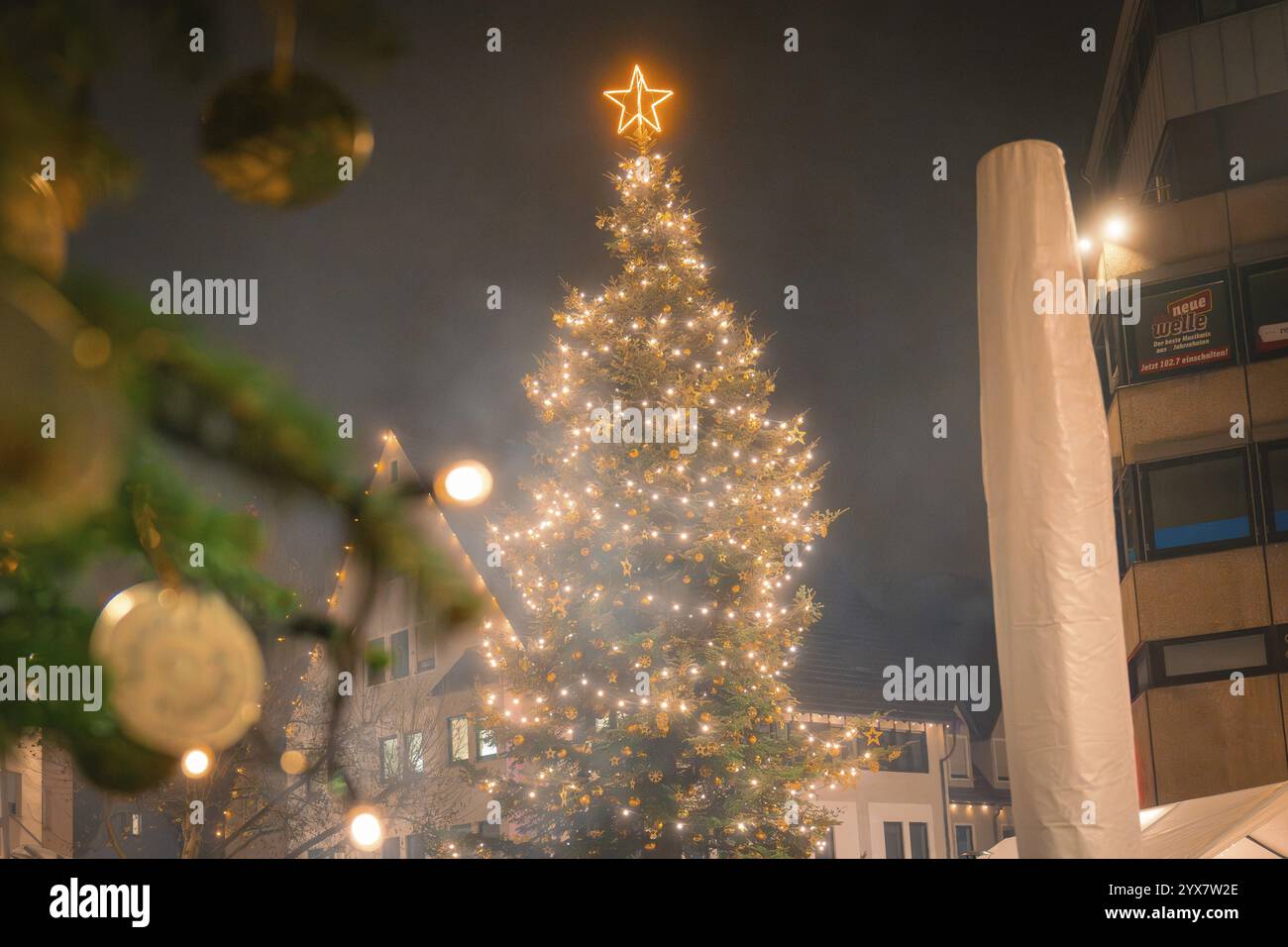 Illuminated Christmas tree at night, surrounded by lights and buildings ...
