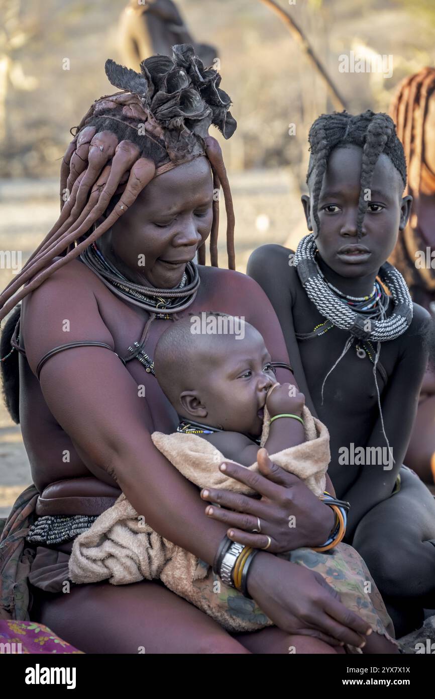 Himba woman with girl and baby in her arms, traditional Himba village ...