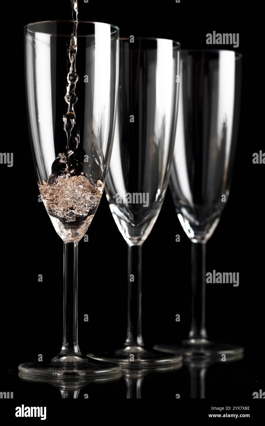 Three champagne glasses in front of a black background, first glass is ...