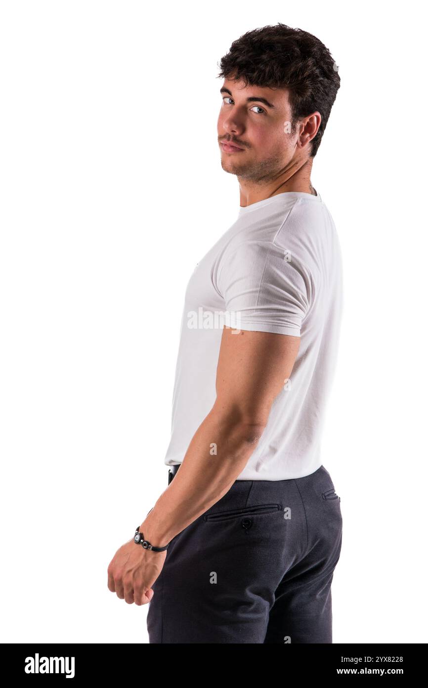 A young man stands with his back turned, glancing over his shoulder. He ...