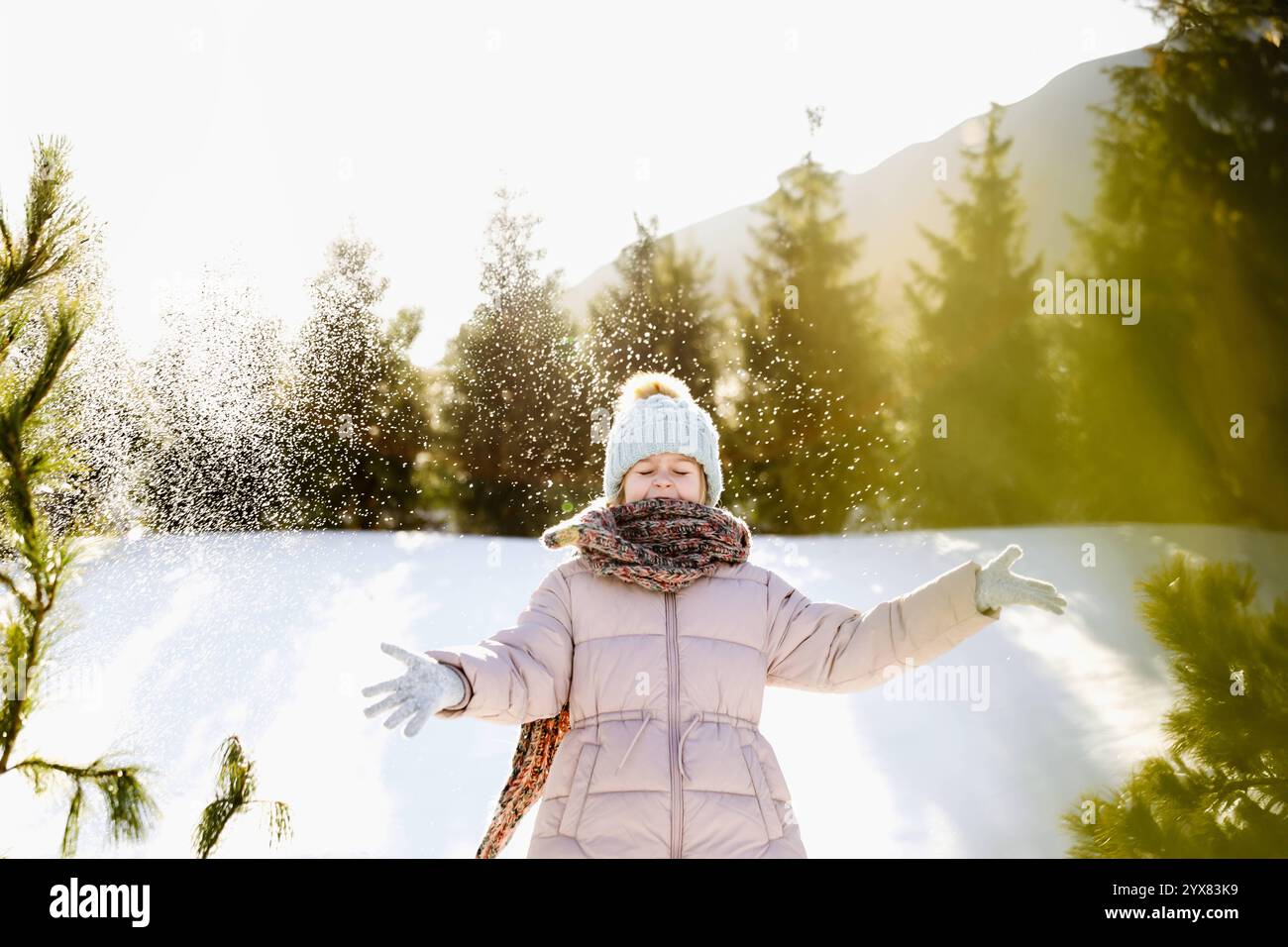 Happy girl playing in winter mountains forest, throwing snow into the ...