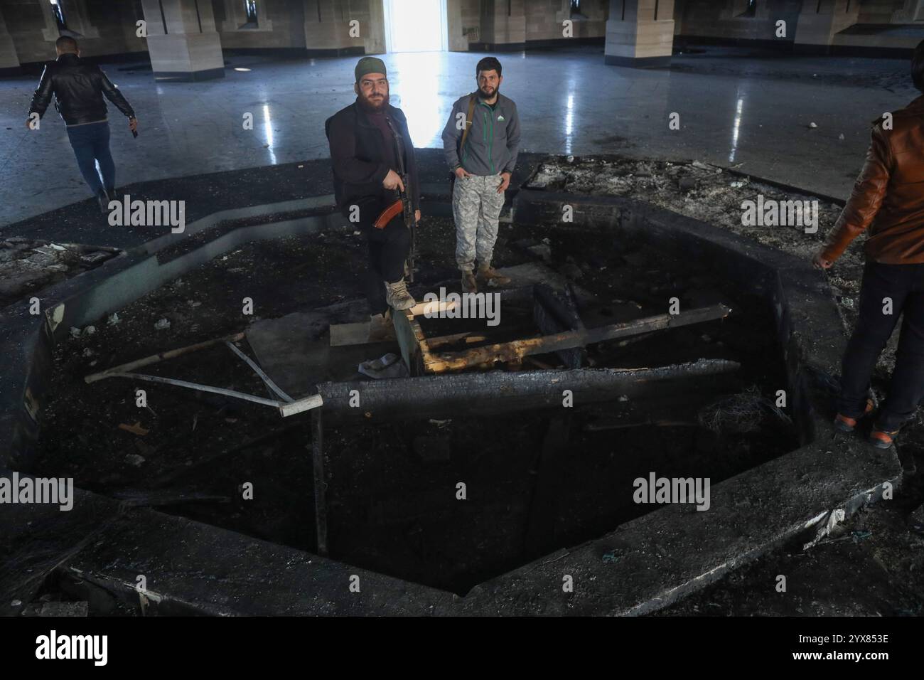Insurgent fighters stand on the burned-out tomb of Syria's former ...