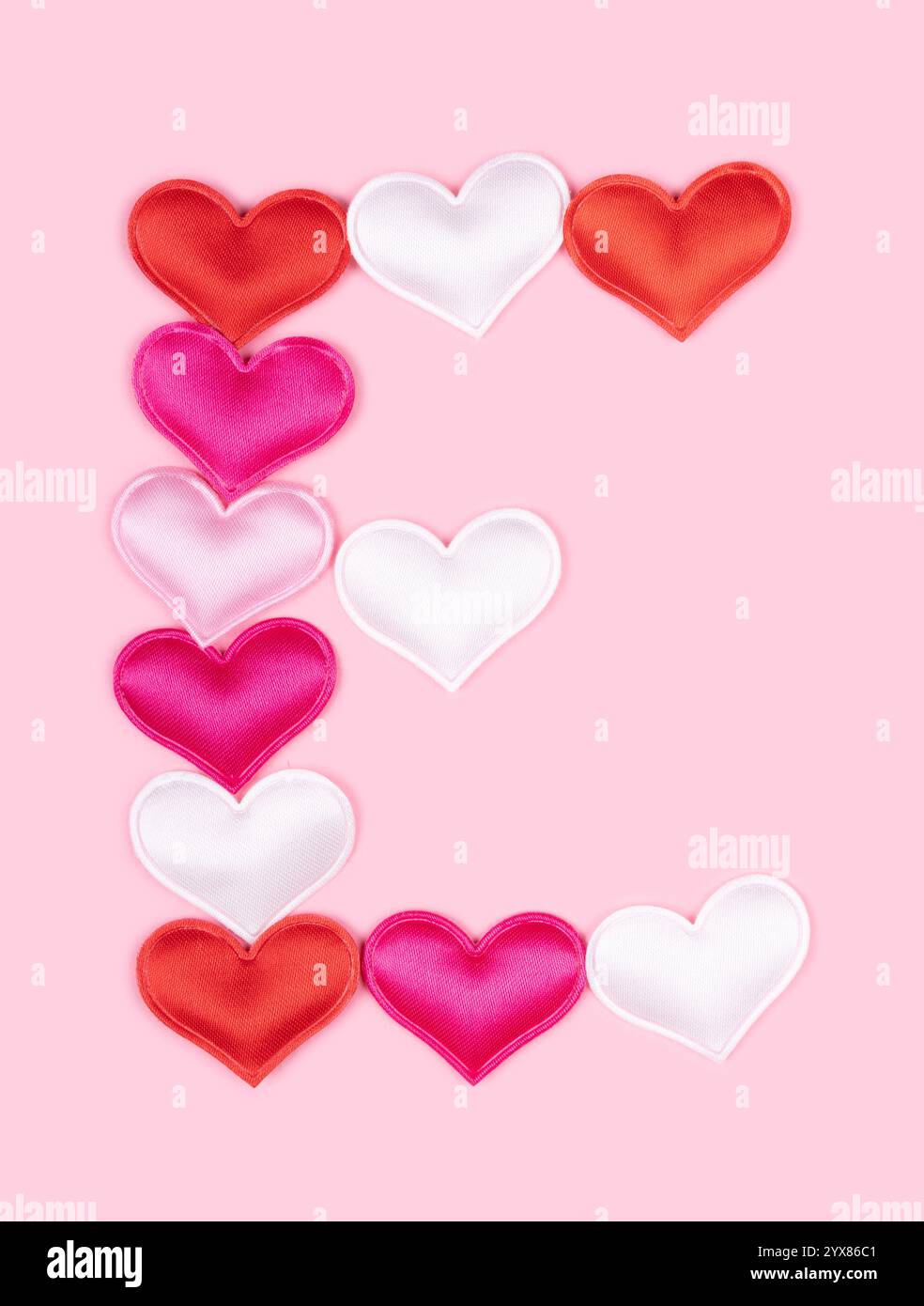 Letter E made of glossy atlas hearts isolated on solid pink background ...