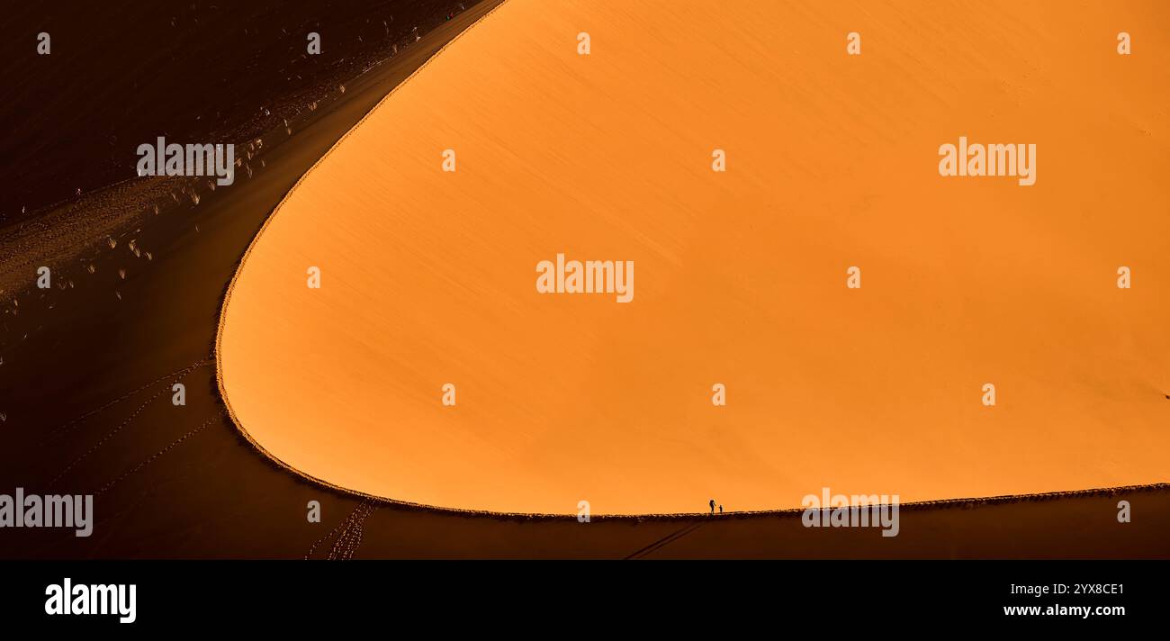 In the distance, people are walking on the ridge of a dune, and there ...