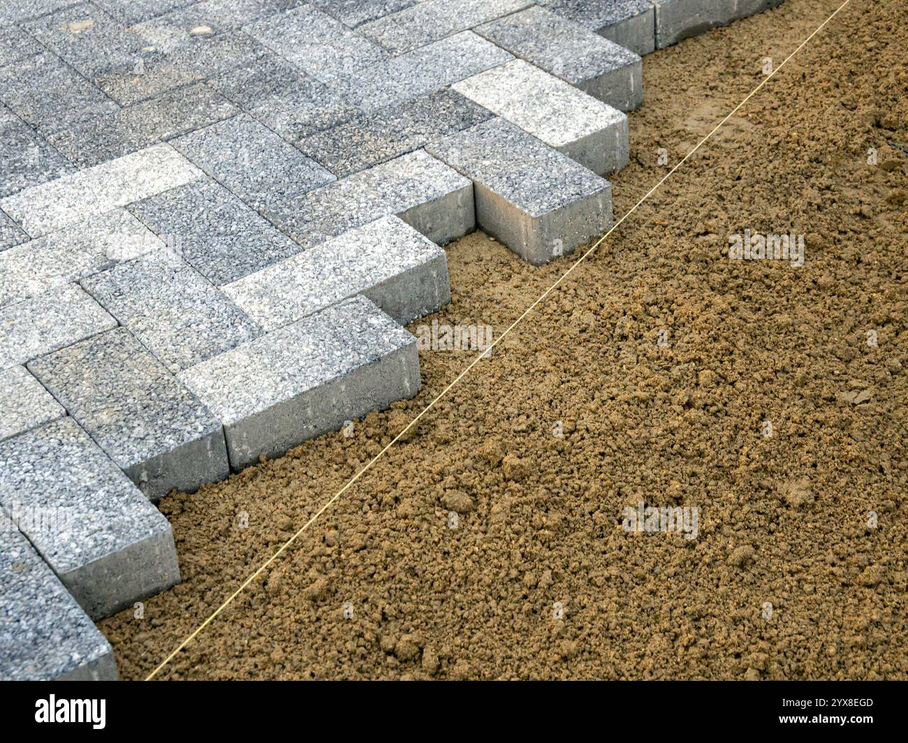 Laying paving slabs in a herringbone pattern using twine Stock Photo ...