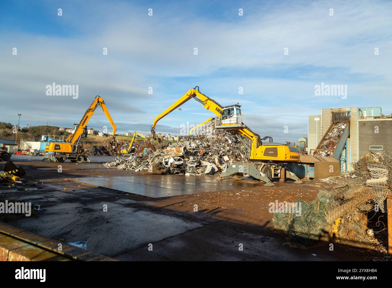Mechanical loader with a grappling arm at a metal recycling facility on ...