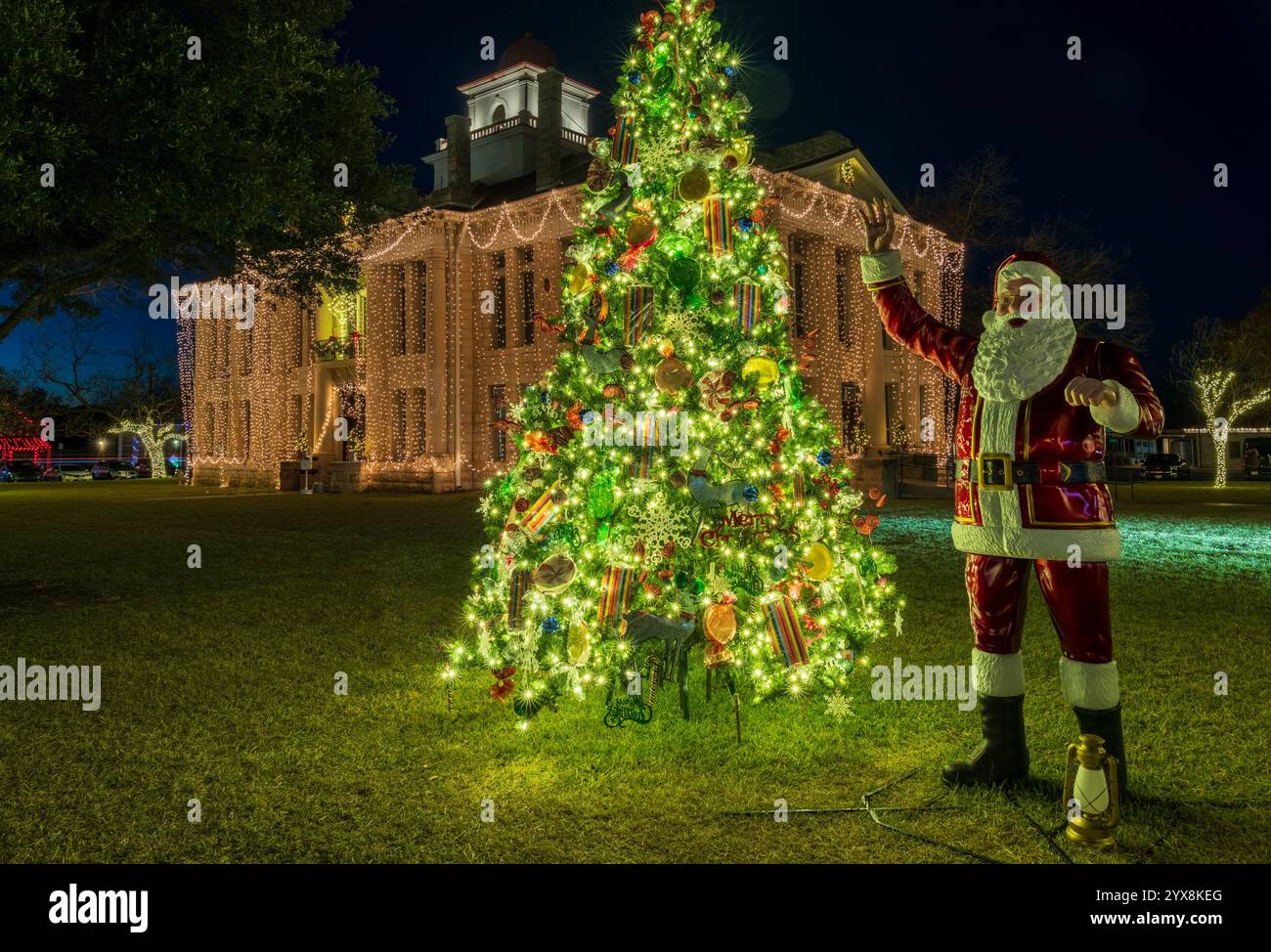 Twinkling lights on Christmas Tree with Santa statue around the ...