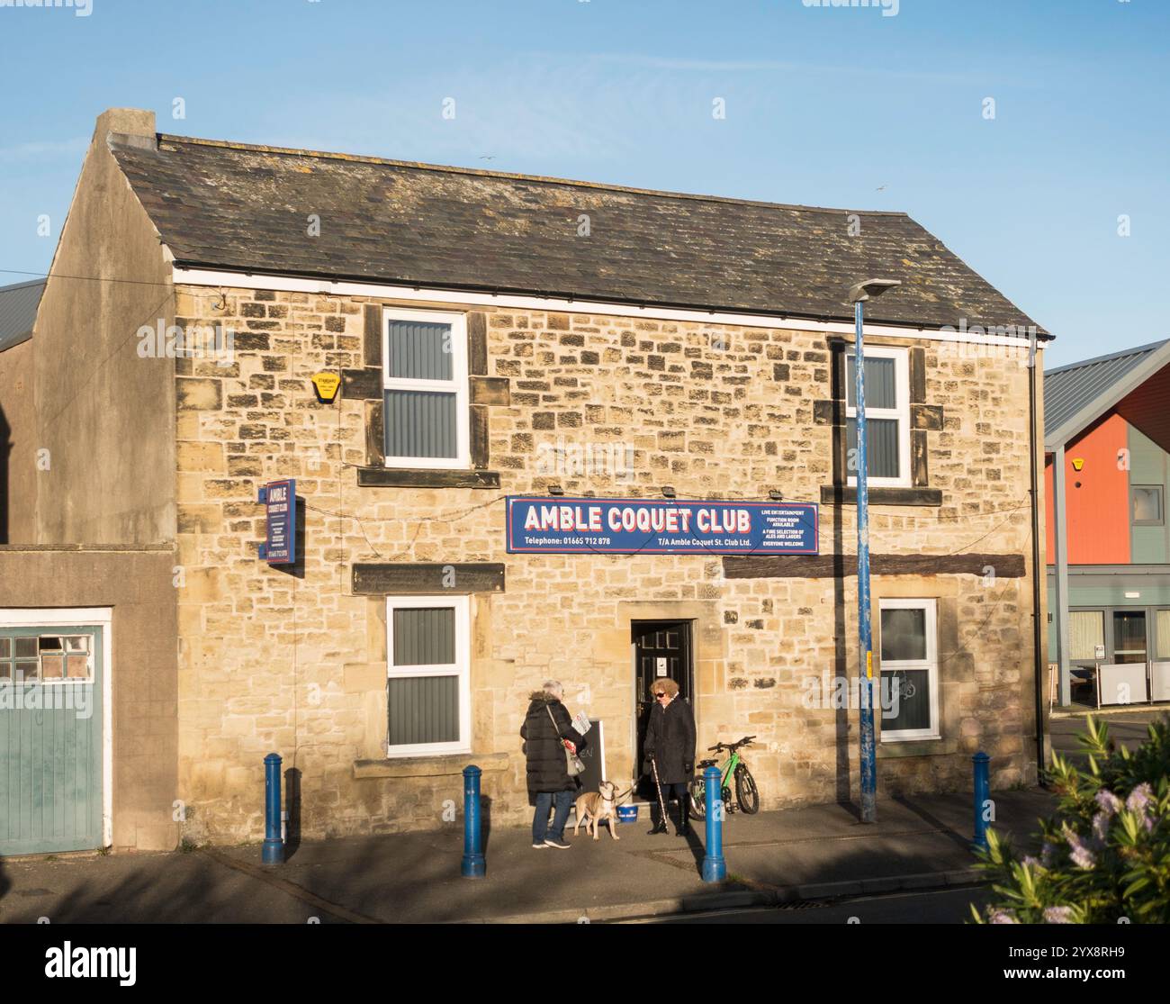 Two women with a dog talking outside Amble Coquet Street Club ...