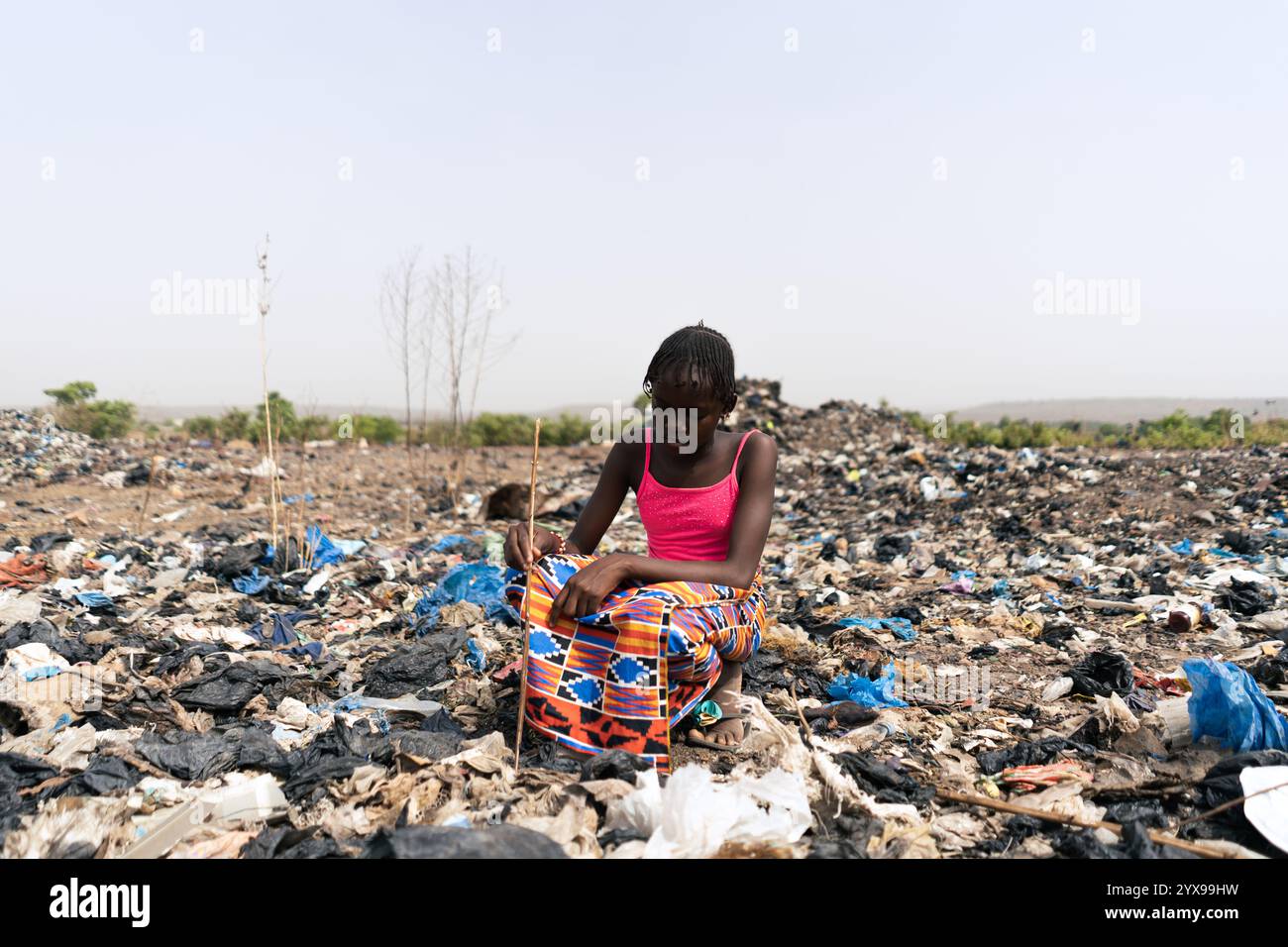 Sad young African girl searching for food and reusable items in a ...