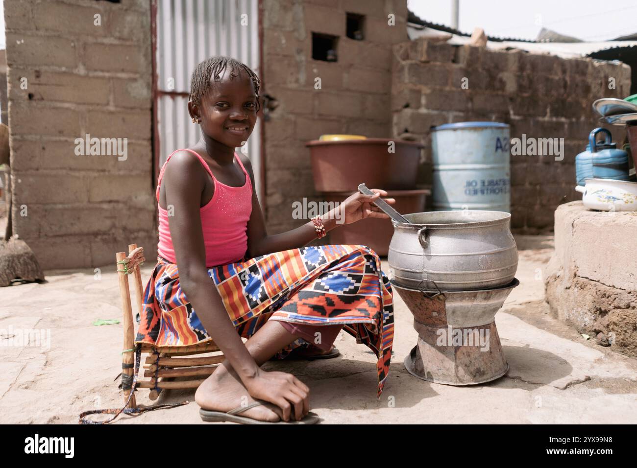 Smiling little African village girl cooking her family's meal in the ...