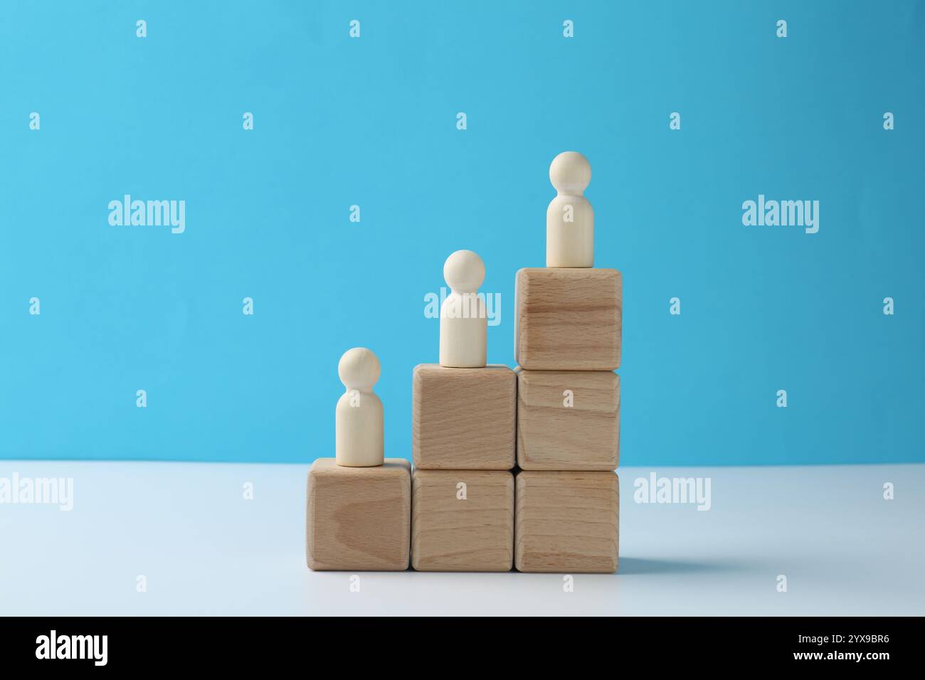 Human figures on stacked wooden blocks on white table against light ...