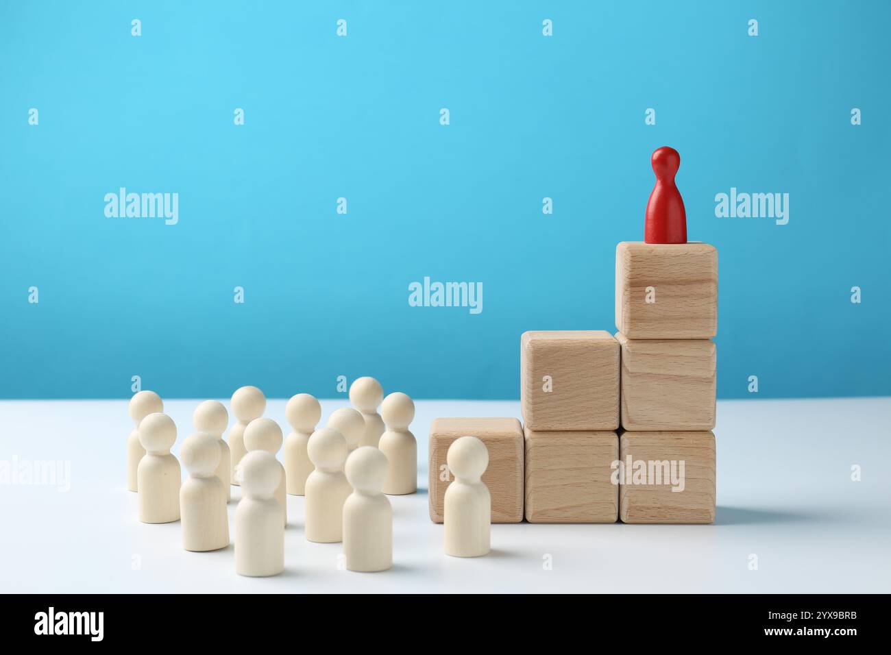 Human figures in front of stacked wooden blocks with red figure on top ...