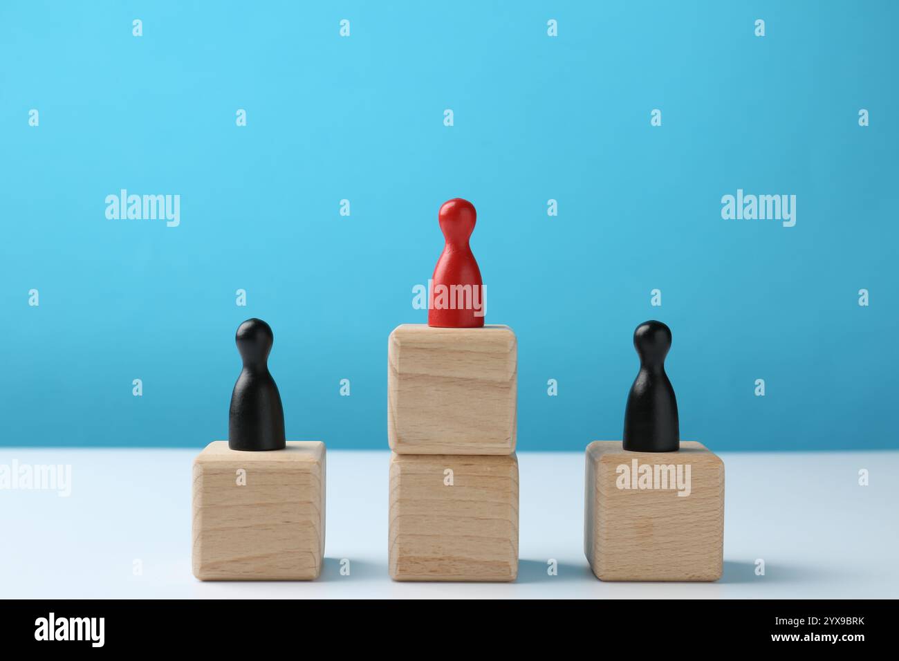 Human figures on wooden blocks, red one on top against light blue ...