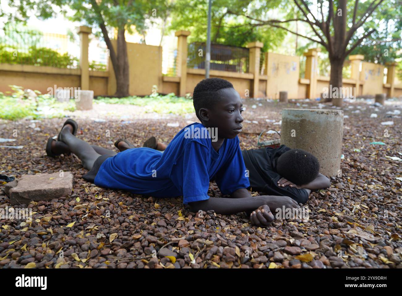 Two homeless African boys in shabby clothes loitering on a wasteland ...