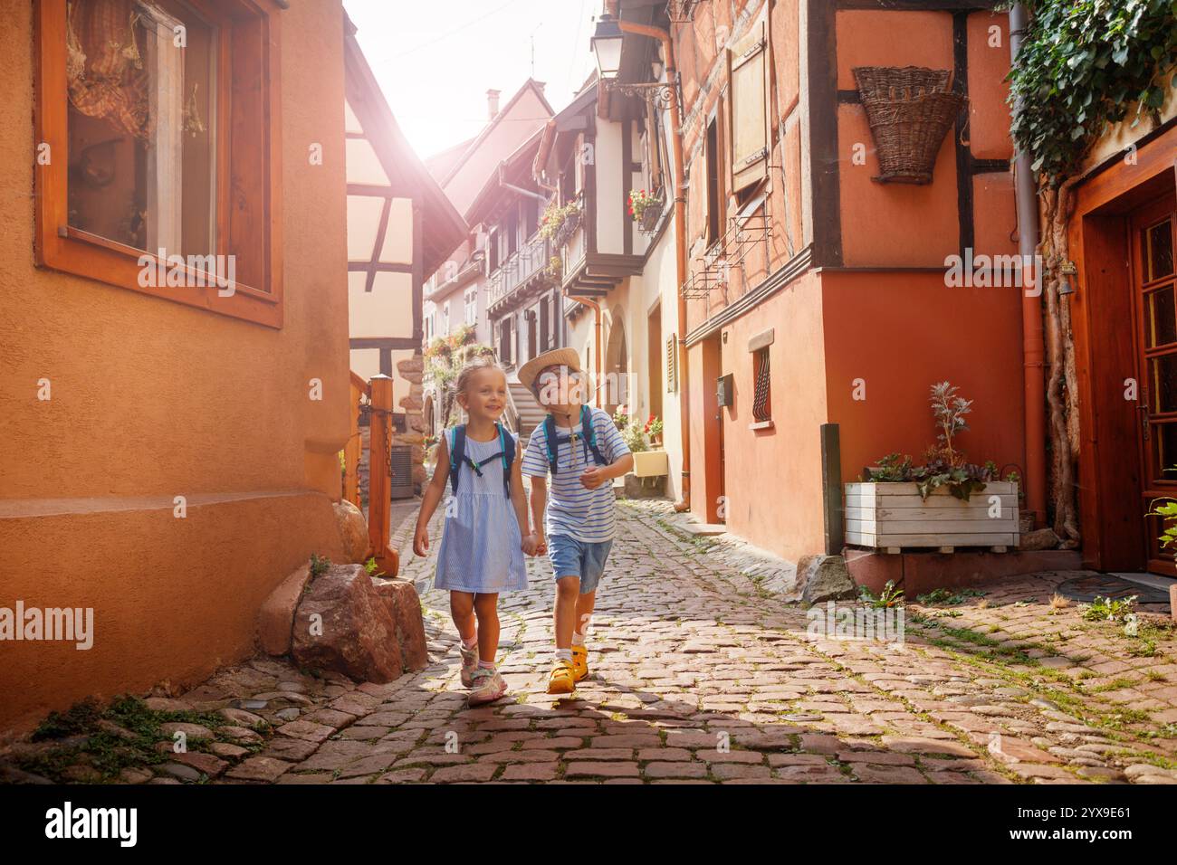 Two children with backpacks walking in old town the buildings have a ...