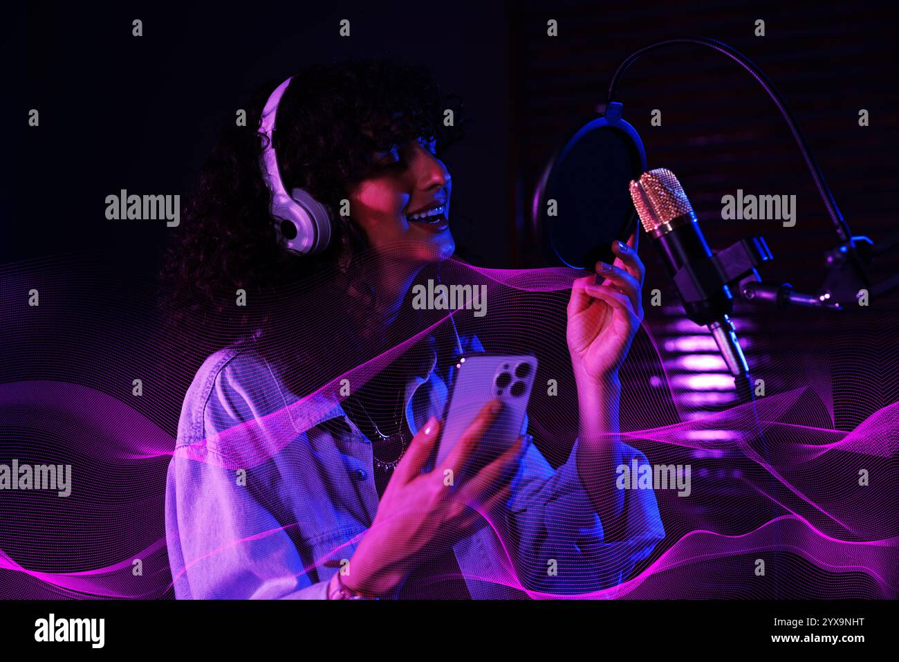 Vocalist with smartphone and headphones singing into microphone in ...