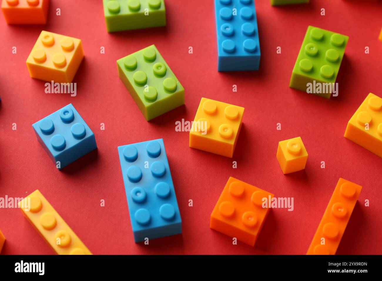 Construction toy. Colorful building bricks on red background, closeup ...