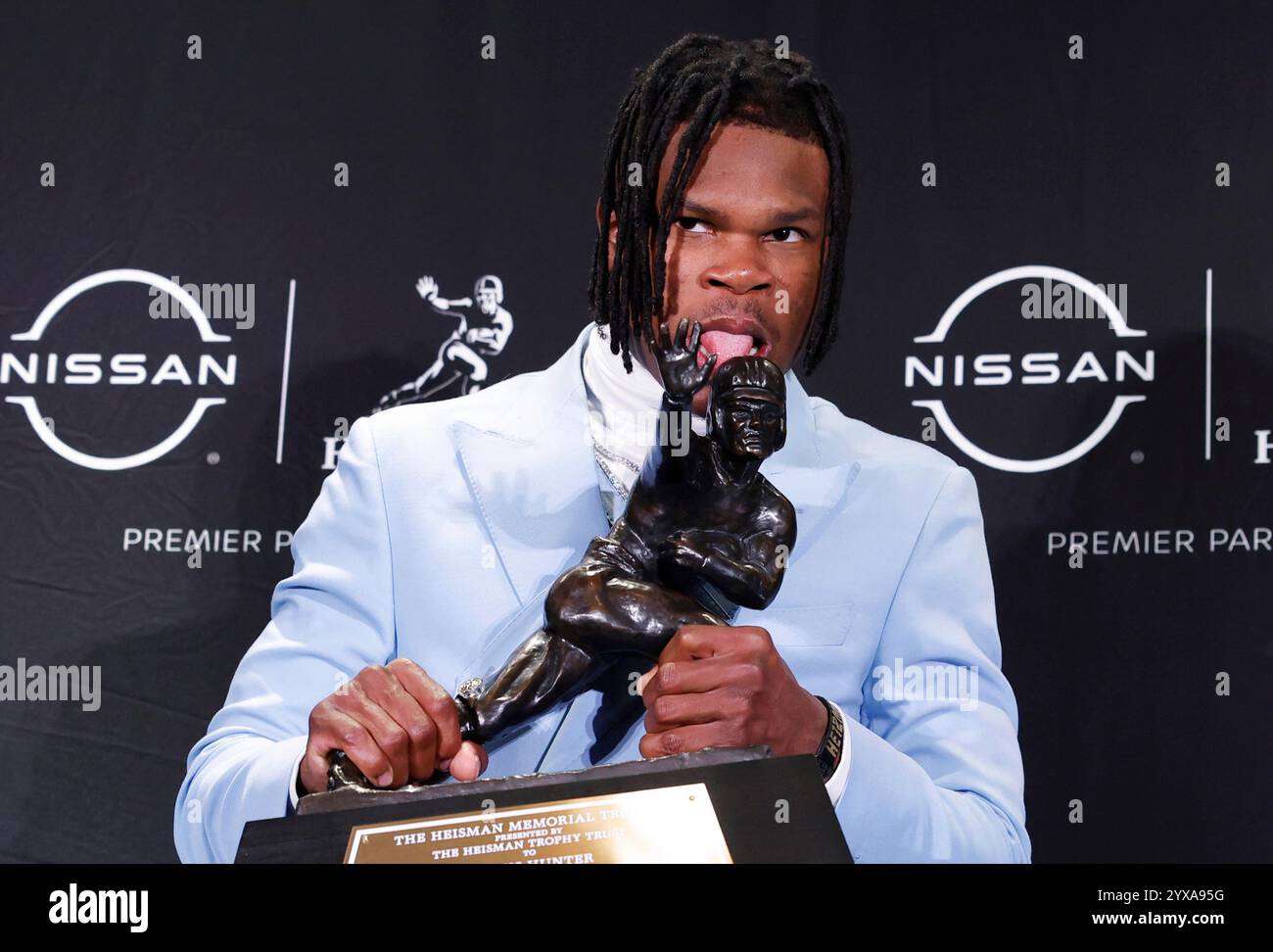 Colorado CB/WR Travis Hunter licks the Heisman Trophy at a post award ...