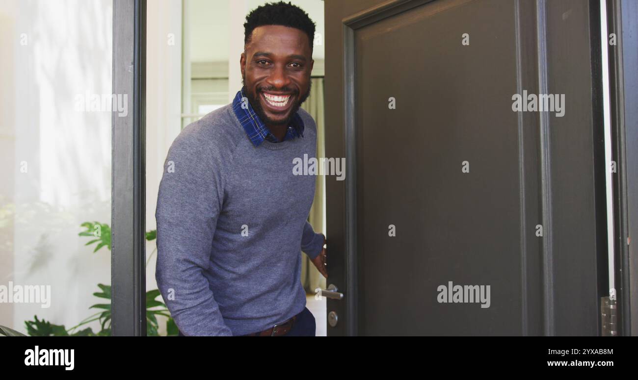 Smiling man opening front door, welcoming guests into cozy home ...