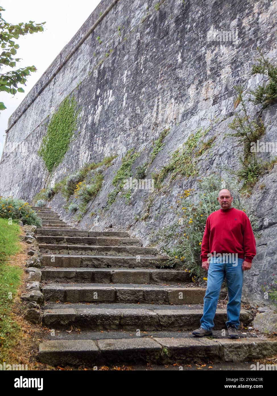 A man stands at the bottom of the steps along an exterior wall of the ...