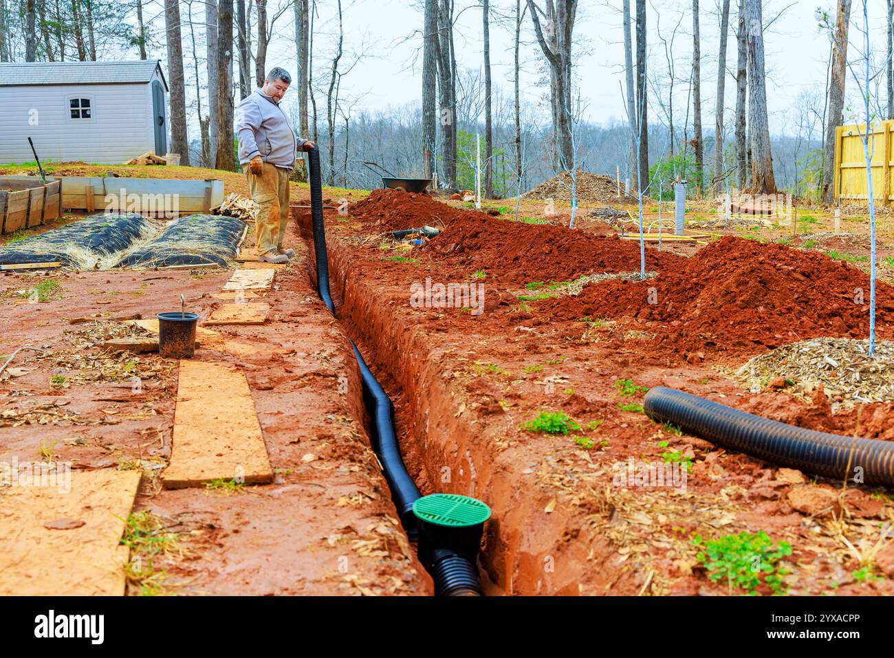 Technical worker works on drainage installation in his garden, managing ...